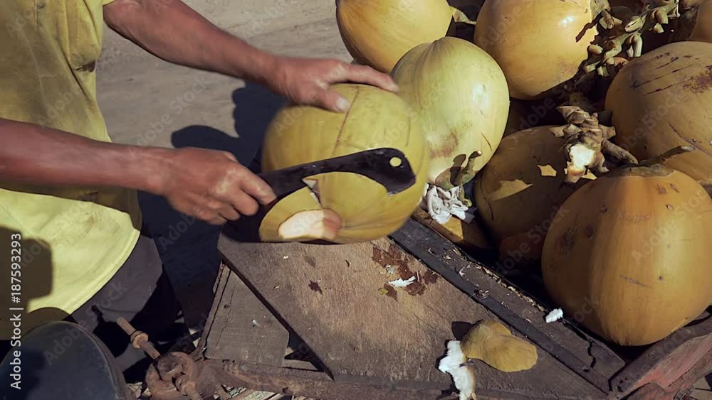 coconut street vendor hacking the top off of a fresh coconut with his ...