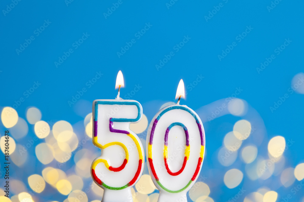 Number 50 birthday celebration candle against a bright lights and blue ...