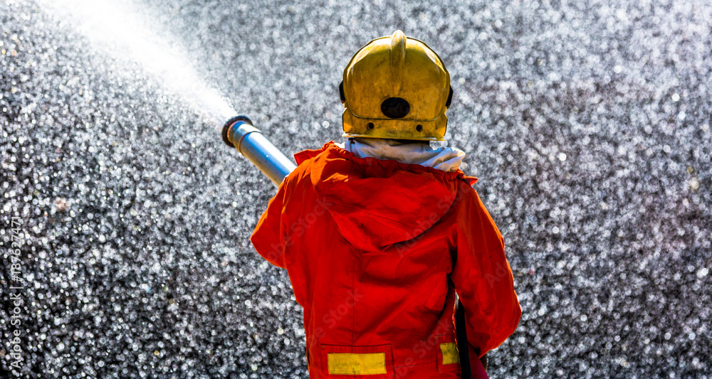 Fireman in helmet and oxygen mask spraying water to fire surround with ...
