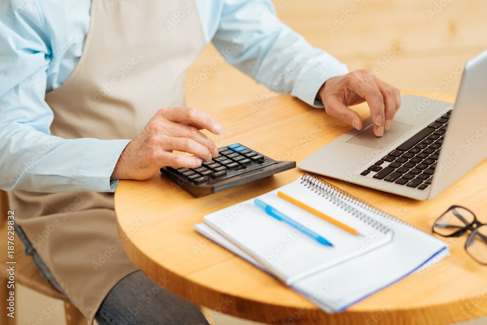 Important process. Senior busy concentrated man sitting by the table ...