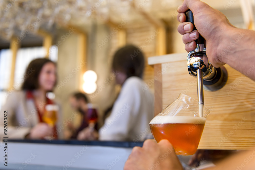 Servir una copa de cerveza artesana en un bar mientras los clientes ...