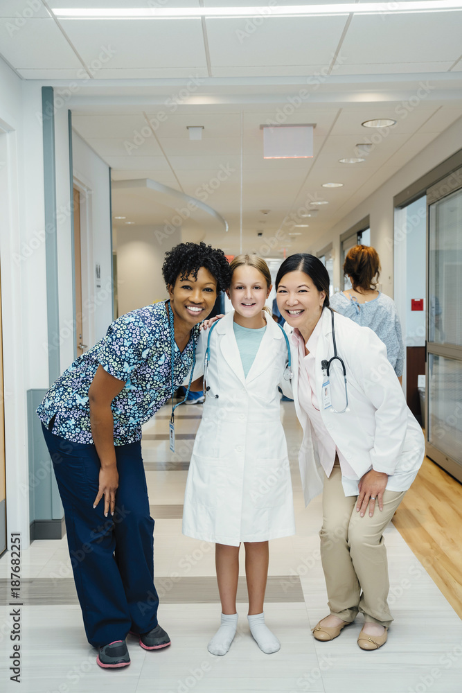 Full length portrait of cheerful female doctors with girl wearing lab ...
