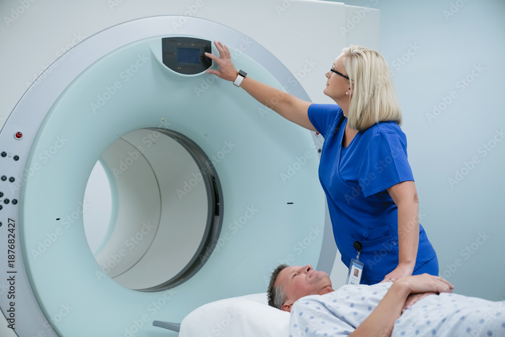 Nurse adjusting button on MRI Scanner while patient lying in ...