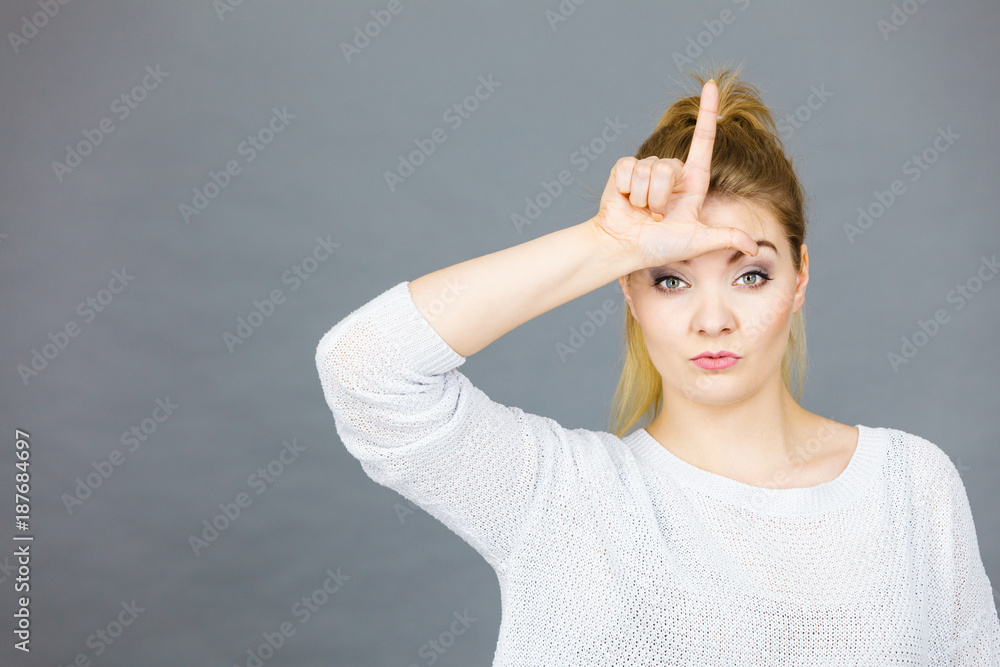 Woman showing loser gesture with L on forehead Stock Photo | Adobe Stock