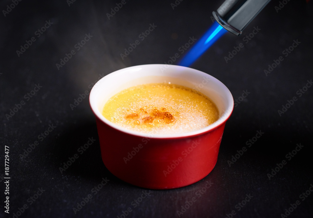 Caramelising sugar on top of creme brulee with flaming torch Stock ...