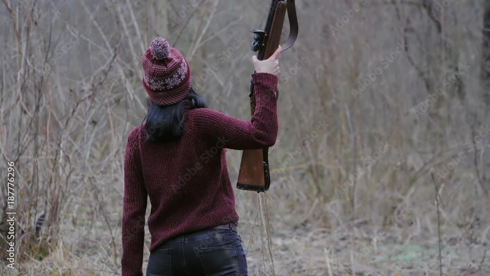 Hunter woman in burgundy warm clothes with gun. Girl hunting in the ...