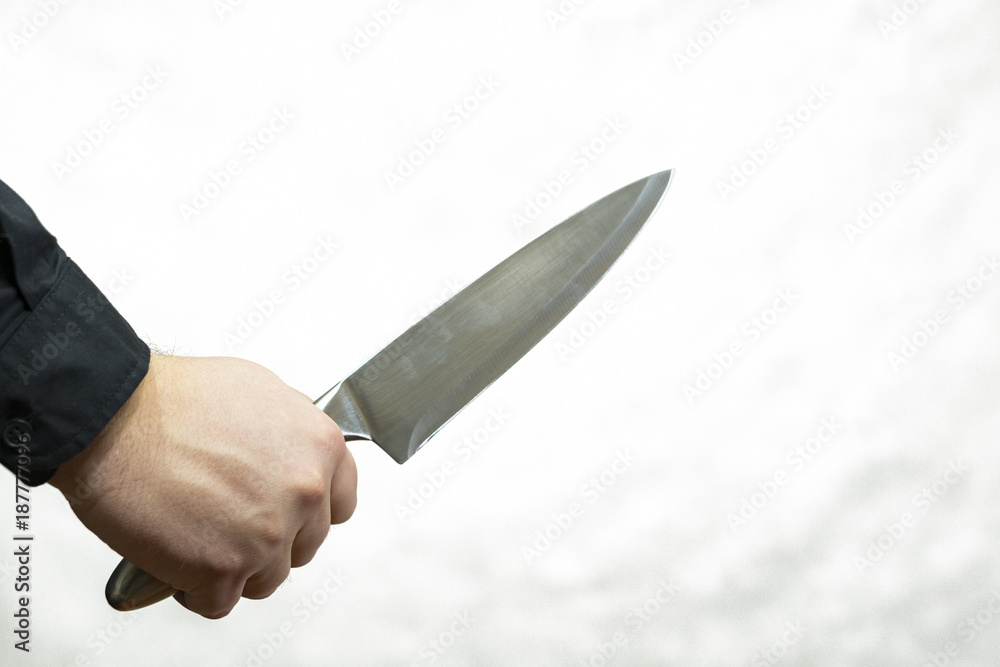 Knife in hand in withe background. The steel shine of the knife blade ...