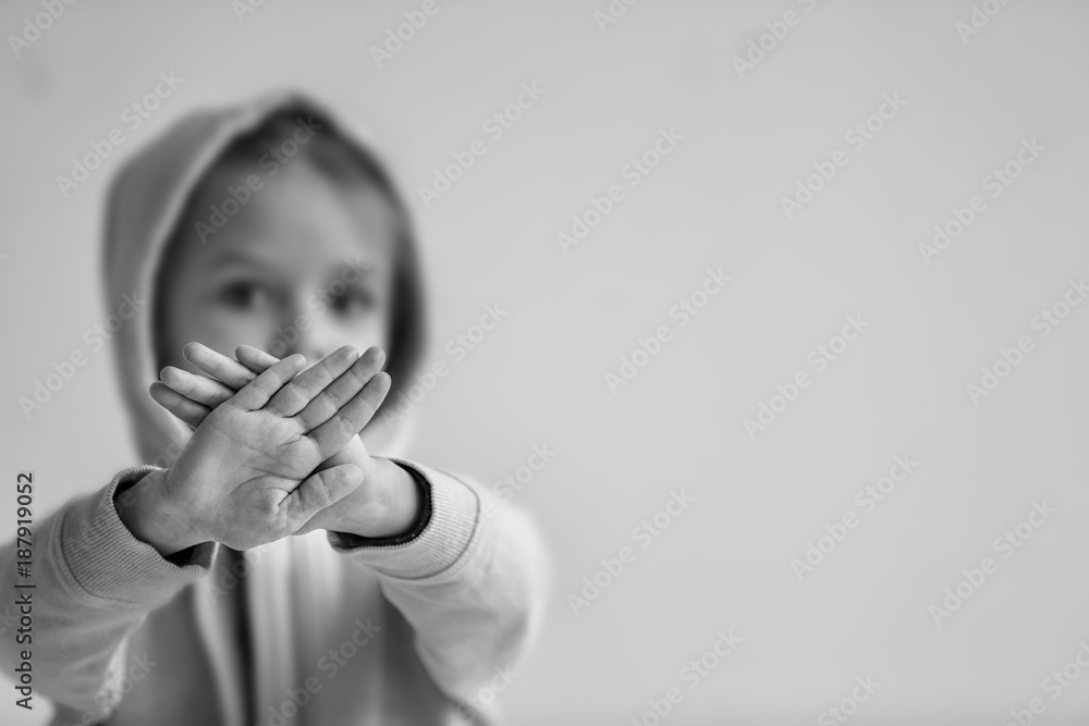 Sad little girl making stop gesture on grey background, black and white ...