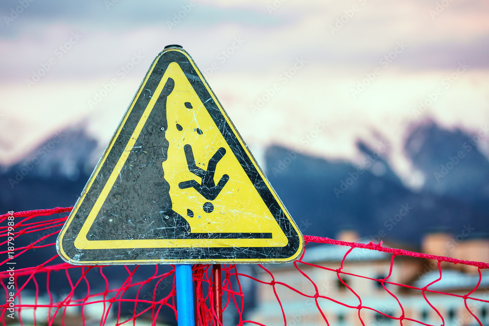Yellow triangle outdoor warning sign on snowy mountain peaks winter ...