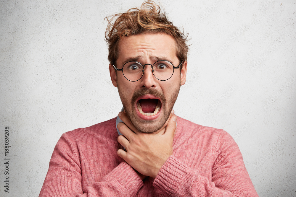 Angry irritated male makes suicide gesture, keeps hands on neck, feels ...