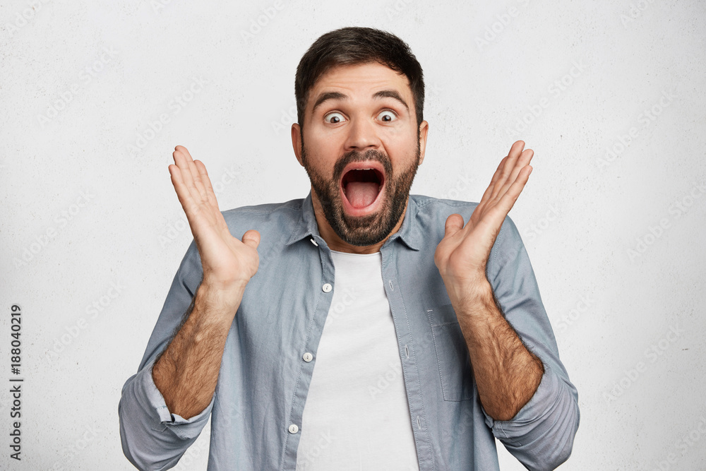 Amazed excited overjoyed male has stubble exclaims in surprisment ...