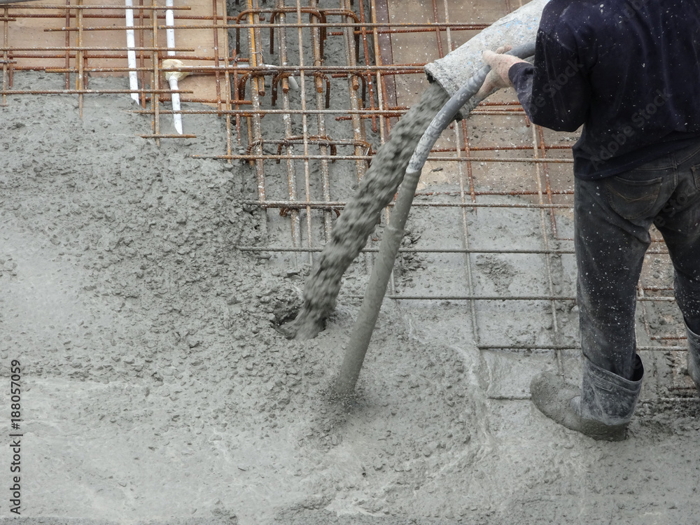 Construction workers pouring wet concrete using concrete spider hose ...