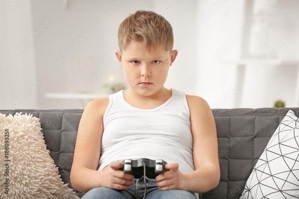 Overweight boy playing video game at home Stock Photo | Adobe Stock