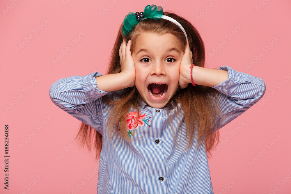 Surprised little girl covering her ears with both hands not listening ...