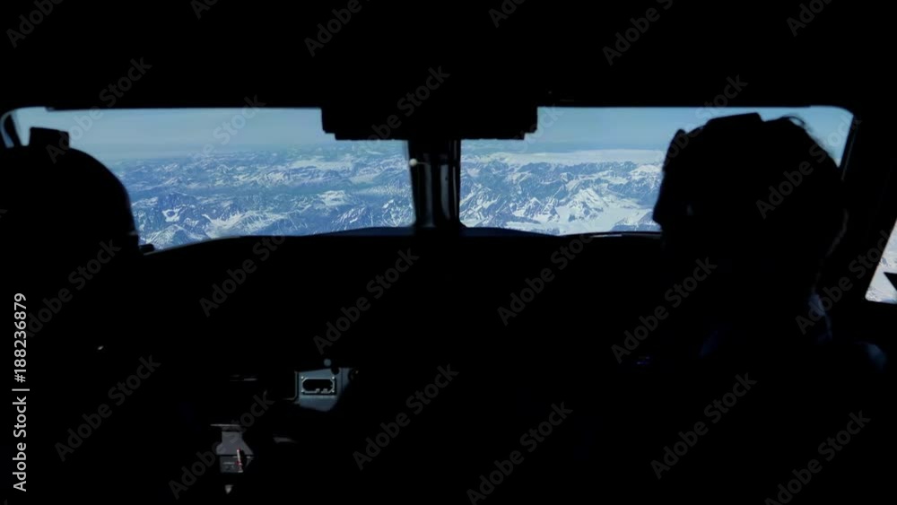 Looking out pilot cockpit window, flying over snowy mountains ...