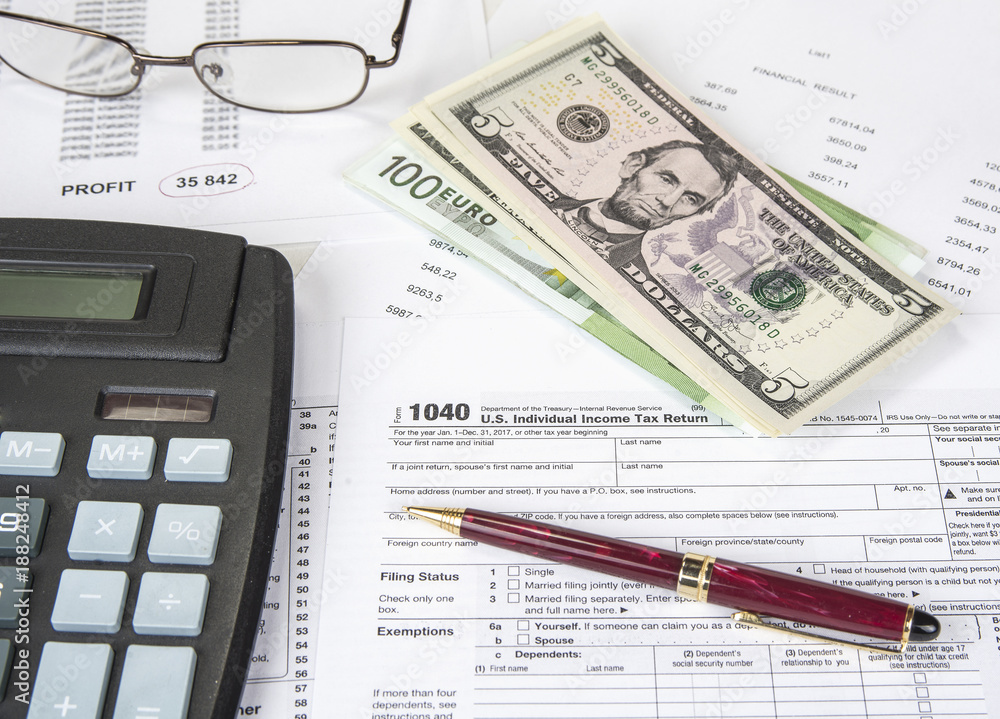 Calculating numbers for income tax return with pen, glasses and ...