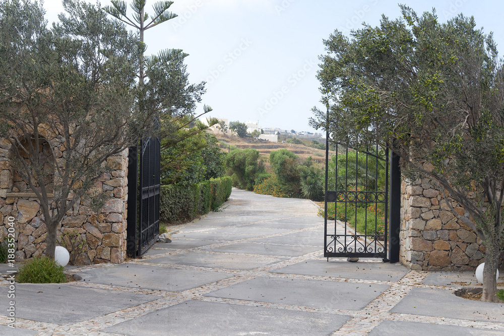 Park entry with open wrought-iron gate in gradient back and shut off ...