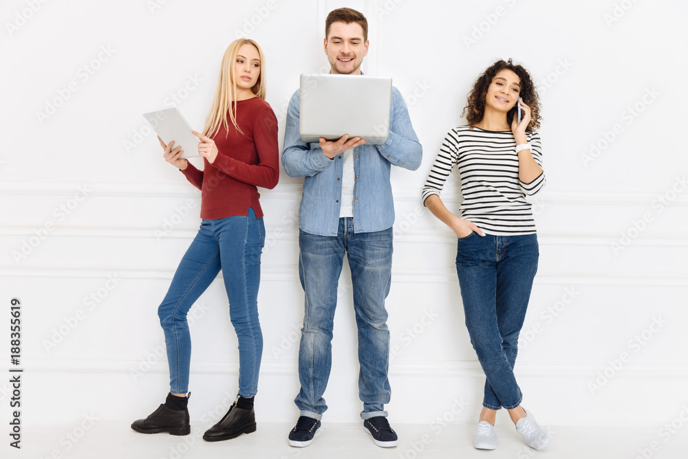 Three friends. Relaxed girl with curly hair talking per telephone and ...