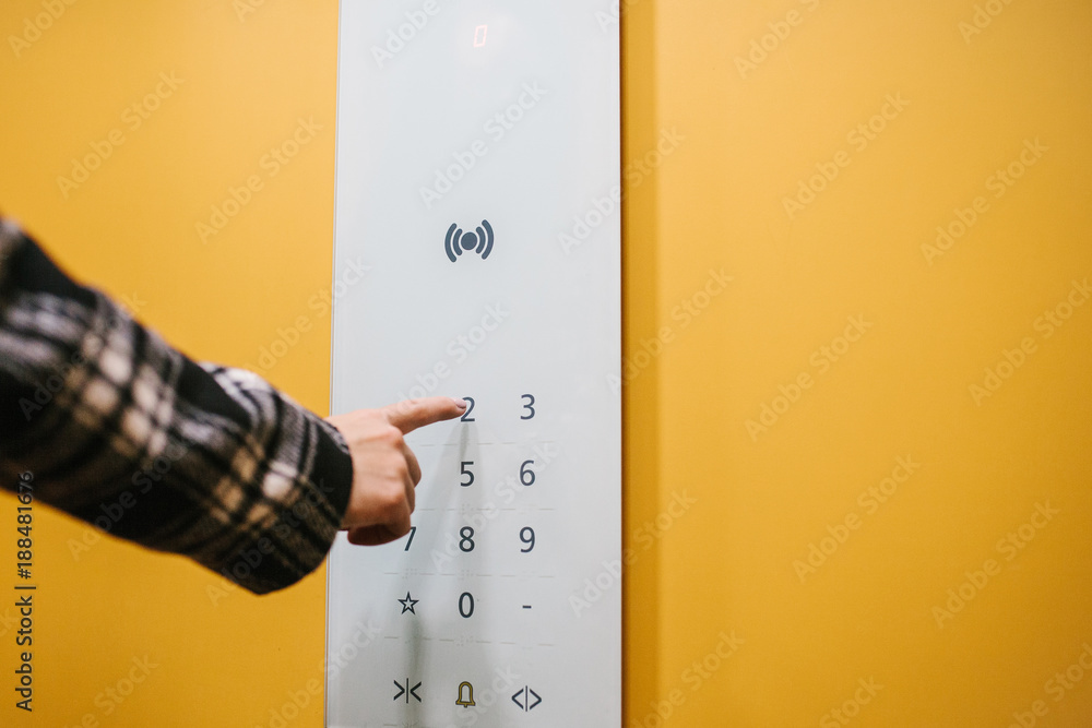 A woman clicks on an electronic button in a modern elevator. Inside the ...