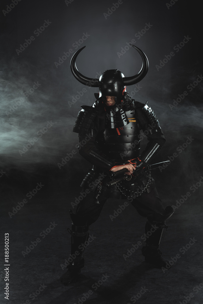 armored samurai taking out his katana on dark background with smoke ...