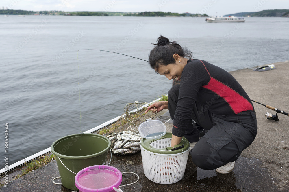 Female fisherman putting caught fish into basket Stock Photo | Adobe Stock