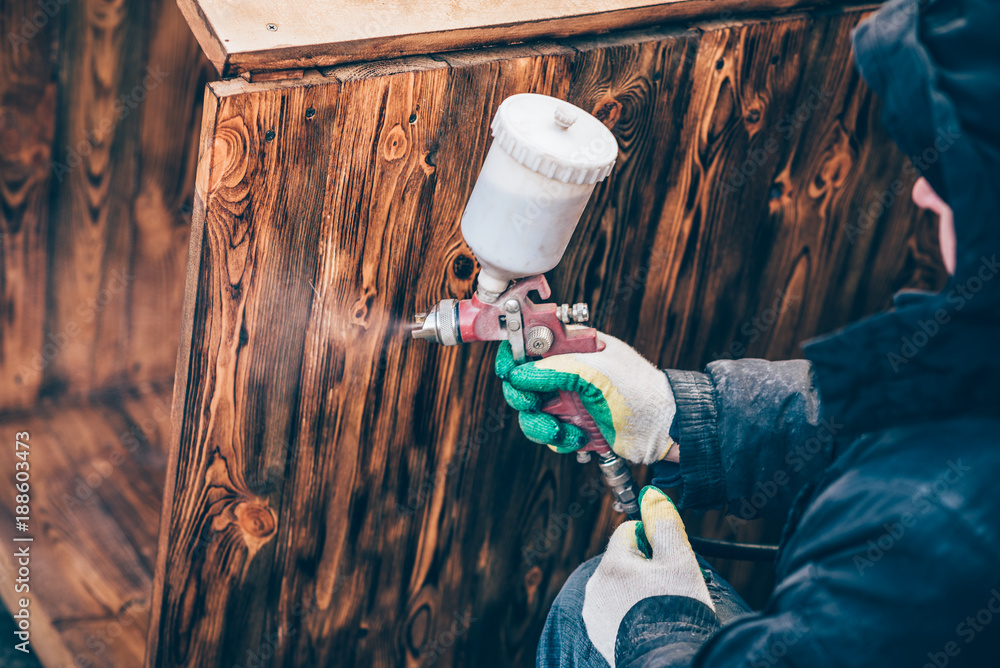 Male painting wood with using spray gun. Man's hand raspiraet paint ...