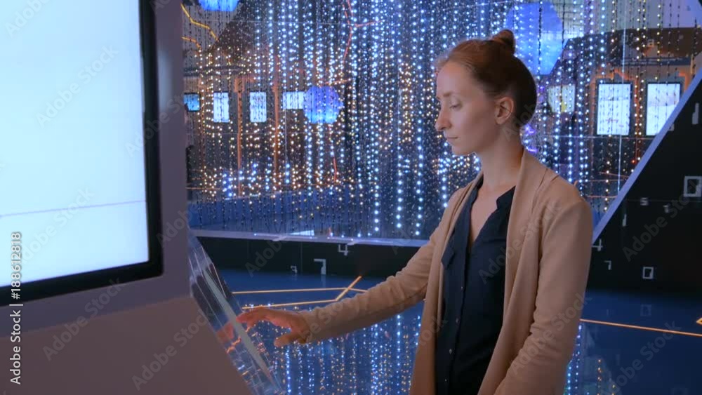 Woman using interactive touchscreen stand and watching video ...