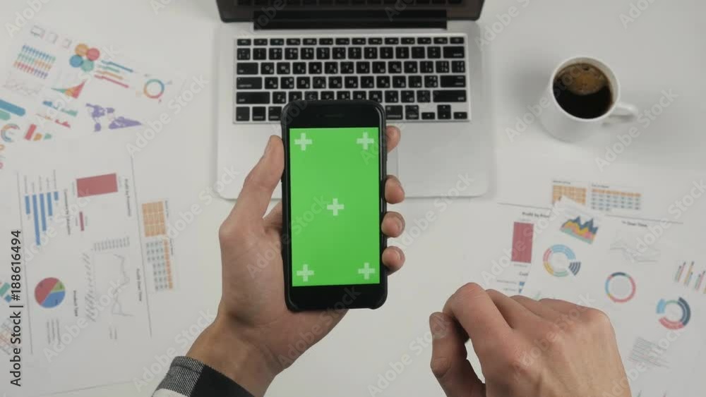Businessman using smartphone with green screen at white office table ...