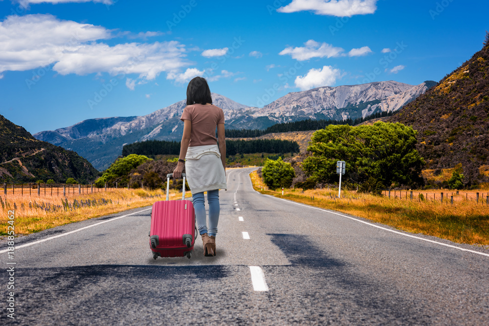 woman walking on the highway road alone with suitcase luggage to the ...