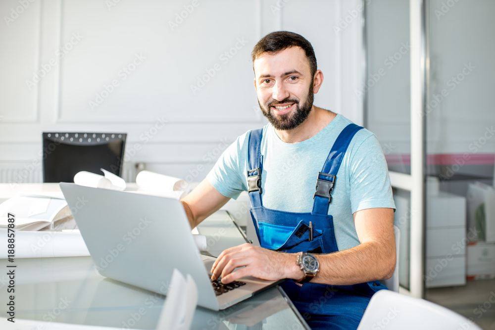 Handsome repairman or foreman in uniform working with laptop and ...