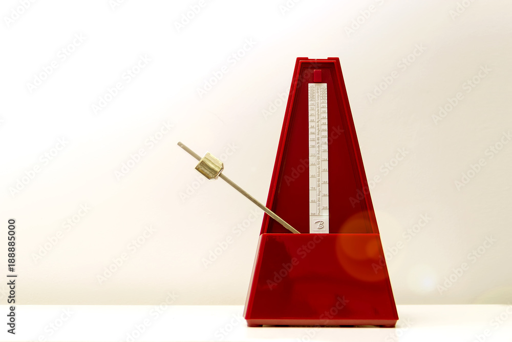 Mechanical metronome of red color on a white background with a light in ...