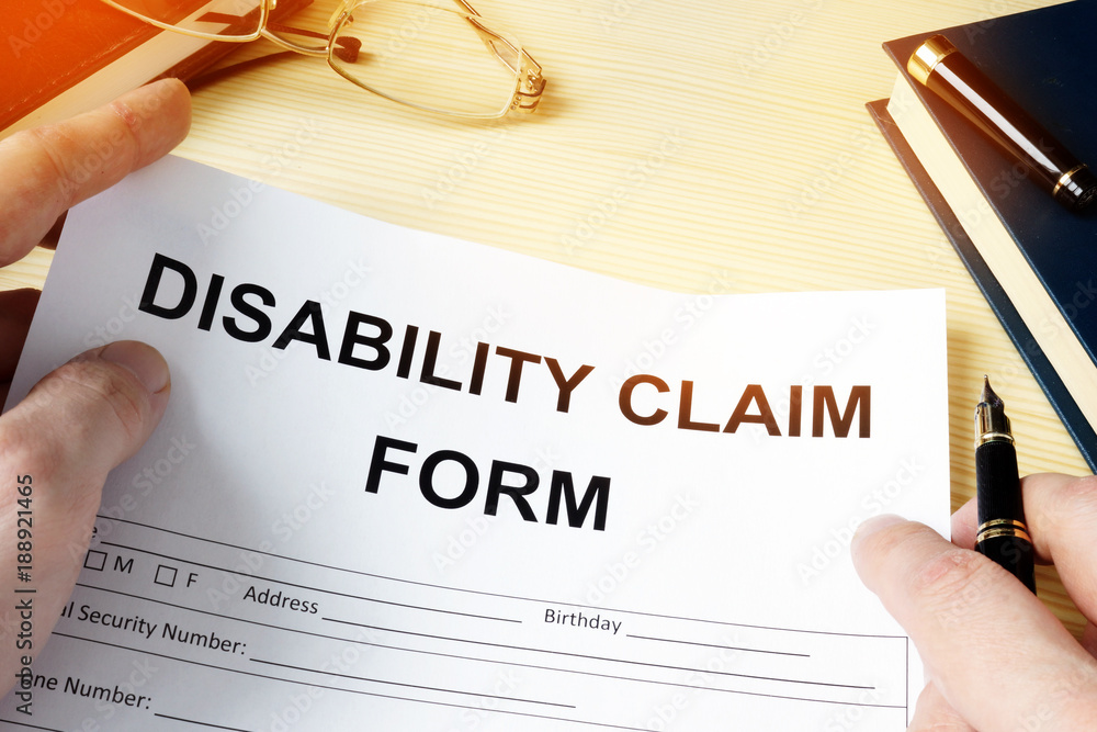 Man holding disability claim form for insurance. Stock Photo | Adobe Stock