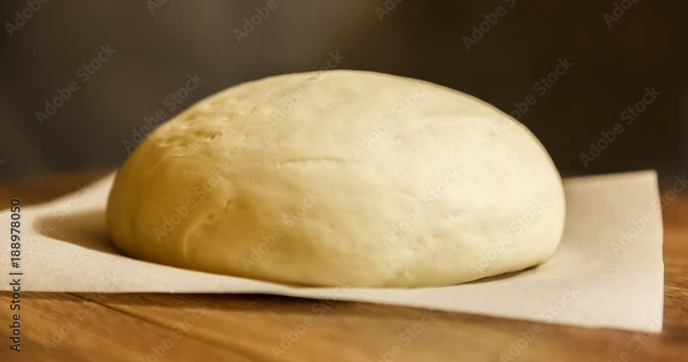 time laps. the dough rise . yeast dough rising on parchment on wooden ...