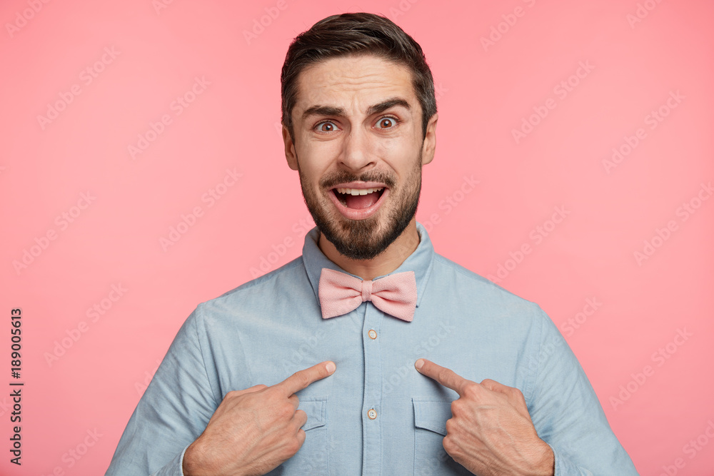 Frustrated male model with dark stubble indicates in bewilderment at ...