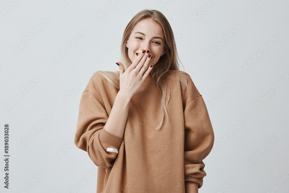 Young cheerful smiling lady covering her face with hand. Carefree ...