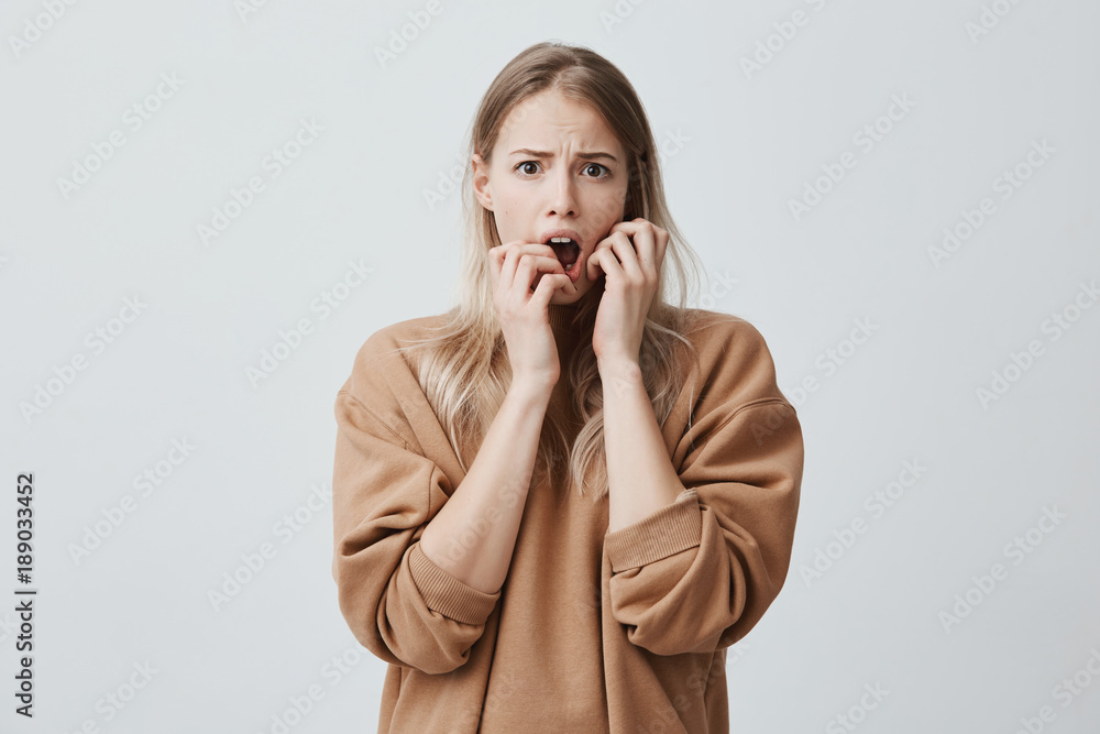 Emotional pretty female with blonde hair stares at camera with dark ...