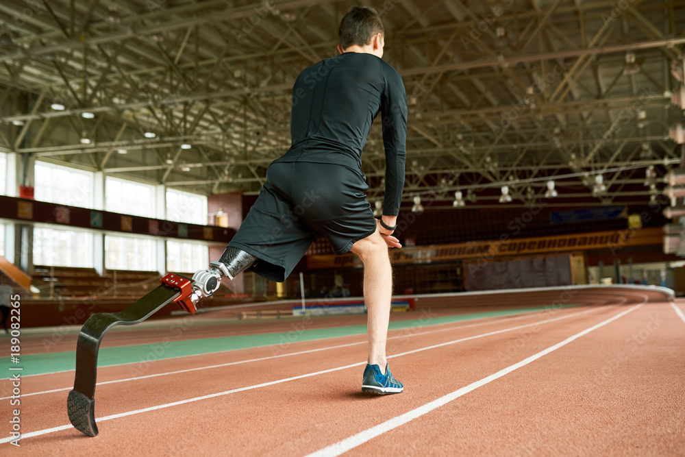 Motivational image of young amputee athlete warming up on running track ...