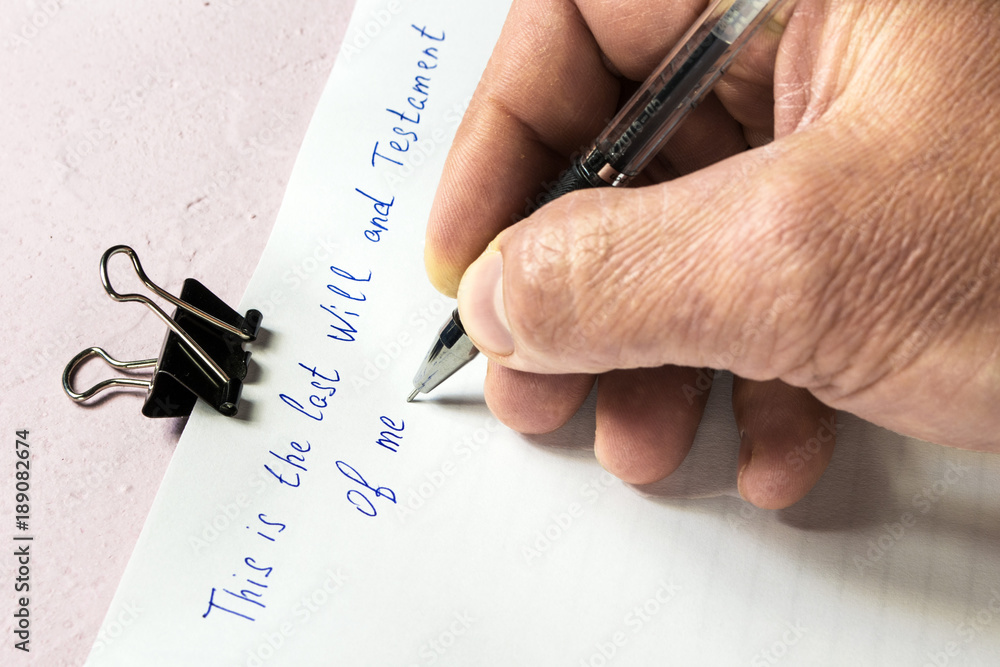 Writing a will. An elderly person writes on a blank sheet of paper ...