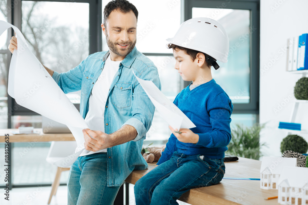 Skilled artists. Cute little boy in a white hard hat holding a picture ...