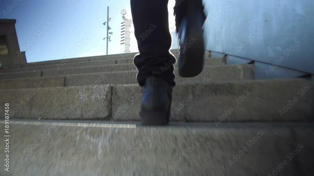 Climbing a stairs, low angle shot. Following some feet that go up a ...