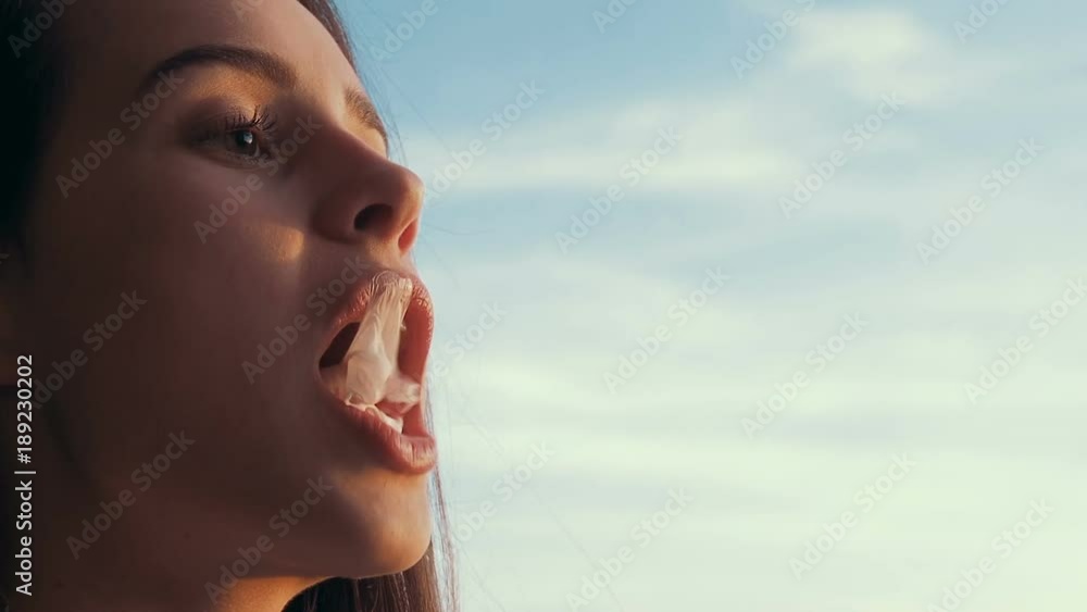 Beautiful girl with a chewing gum on a background of the sky. A teenage ...