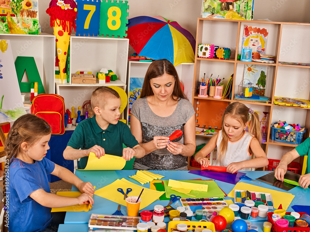 School children with scissors in kids hands cutting paper with teacher ...
