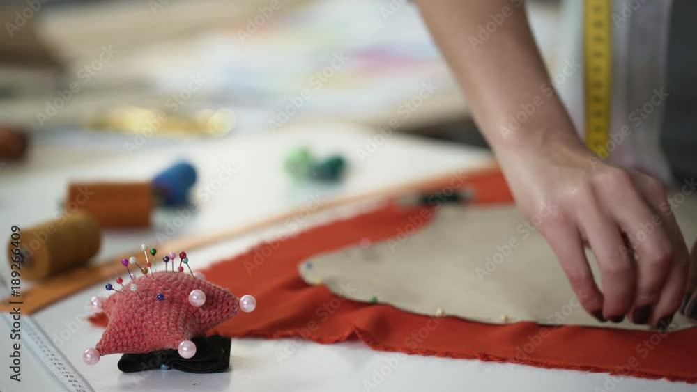 Girl taking pins from needles pad and fixing template on fabric before ...