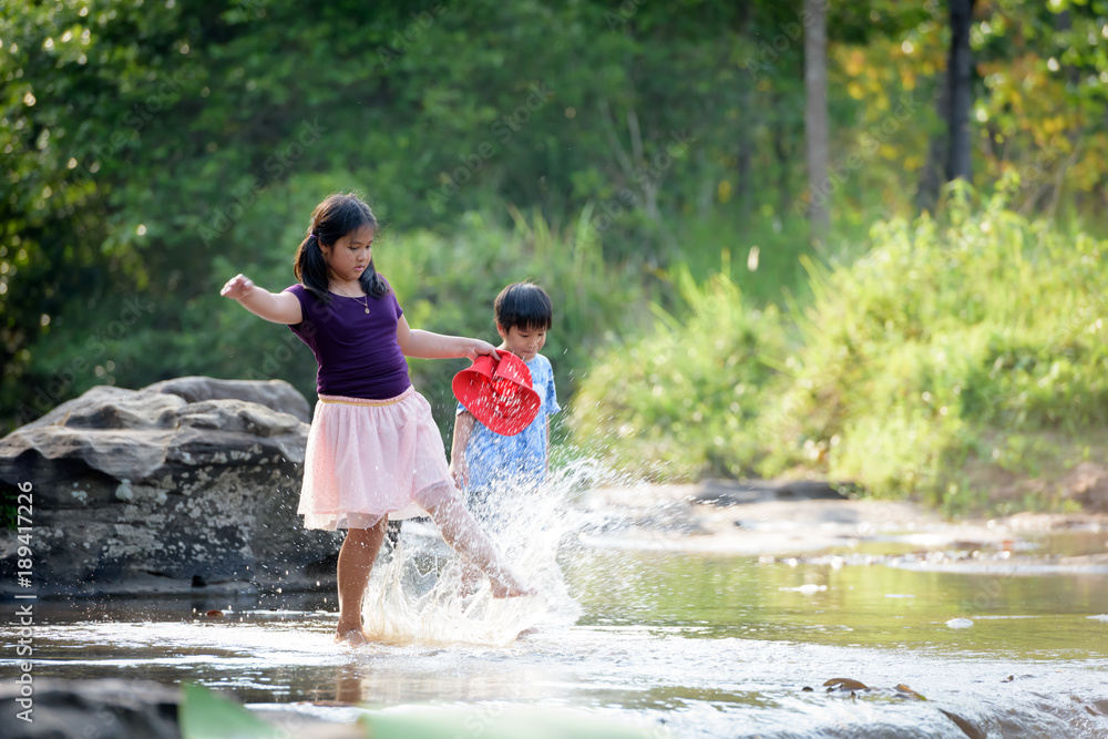 Poster Sister and brother are playing a waterfall in the rain forest on ...