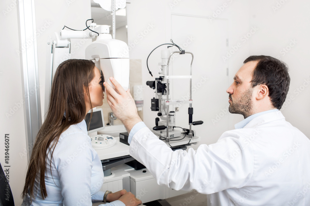 patient woman having her eyes examined by an optometrist using ...