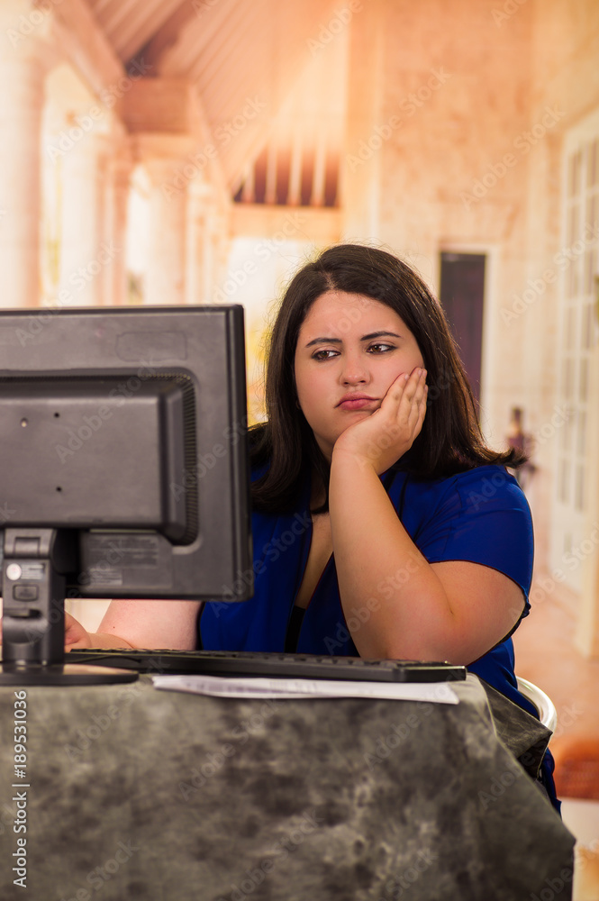 Portrait of tired fat woman working on laptop while sitting in front of ...