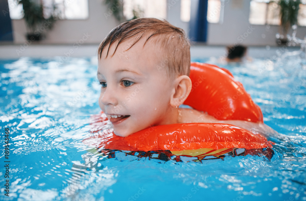 Portrait of happy white Caucasian child in swimming pool. Preschool boy ...