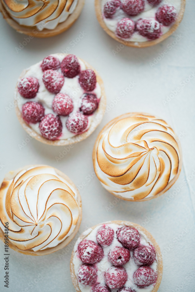 Delicious lemon and raspberry tartlets with meringue on a white vintage ...