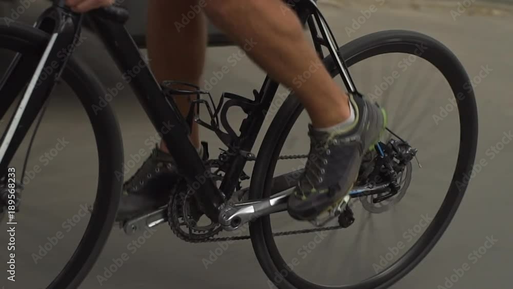 Legs of a man on a bicycle riding along the street rapid slow motion ...