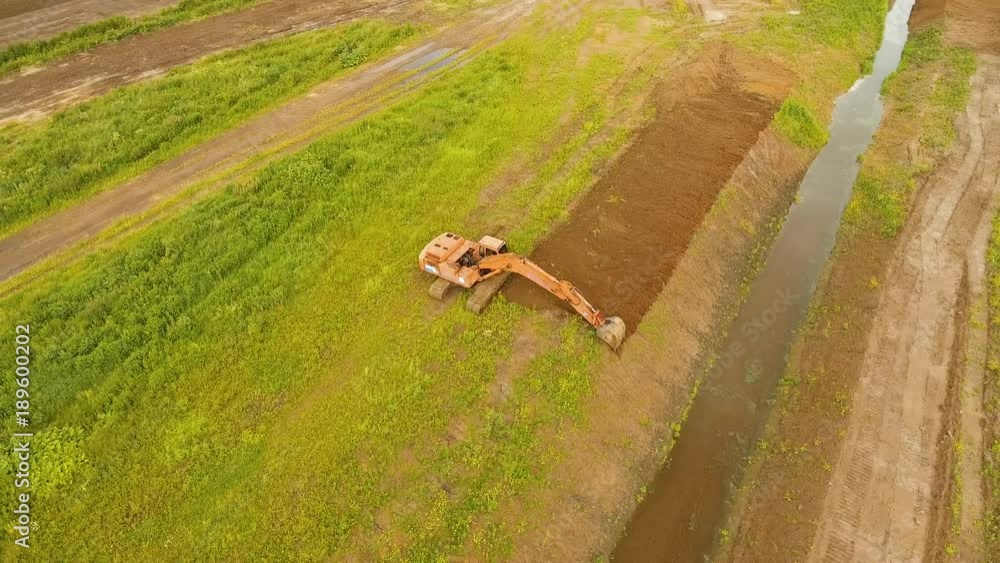 Excavator is digging an irrigation canal. Aerial view:Excavator digging ...